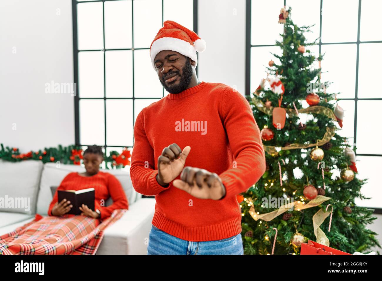Young african american man standing by christmas tree disgusted ...