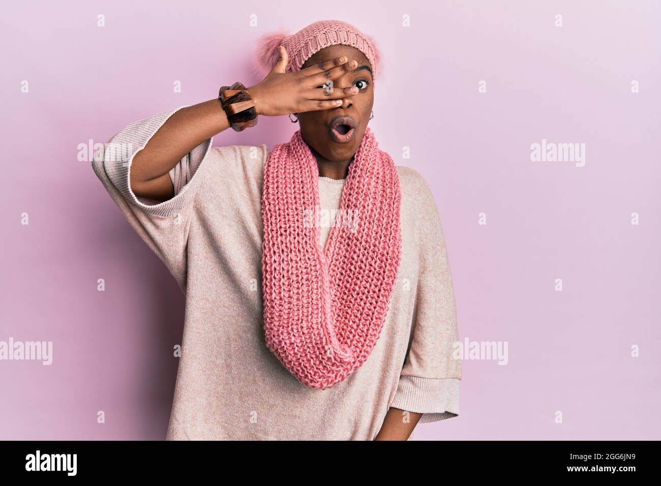 Young african american woman wearing wool hat and winter scarf peeking ...