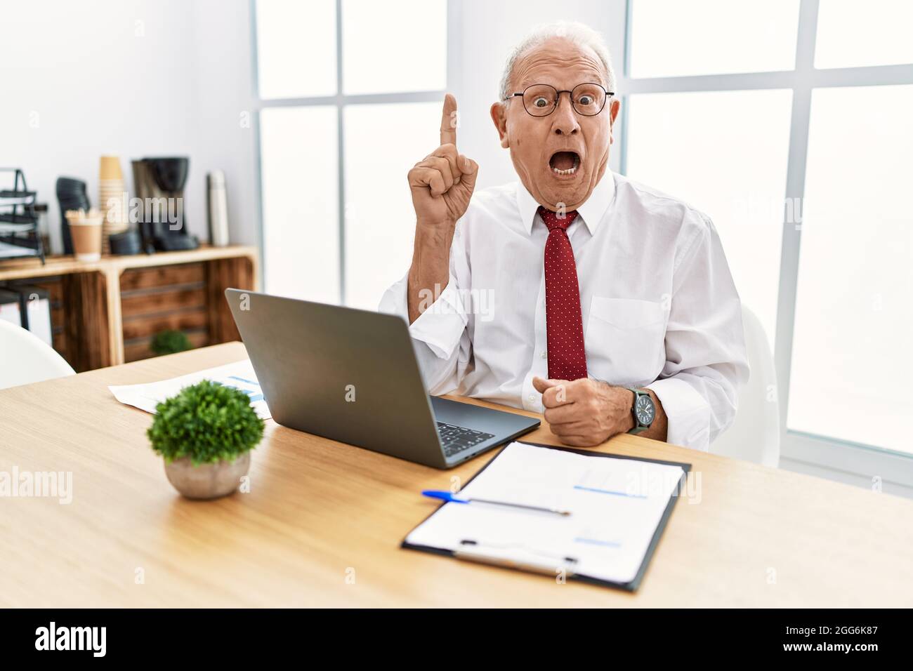 Senior man working at the office using computer laptop pointing finger ...