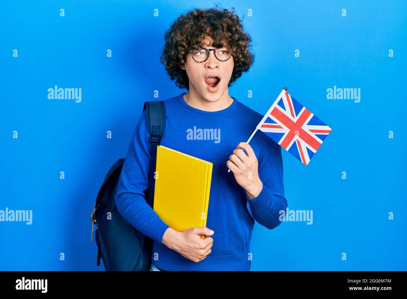 Handsome young man exchange student holding uk flag angry and mad ...