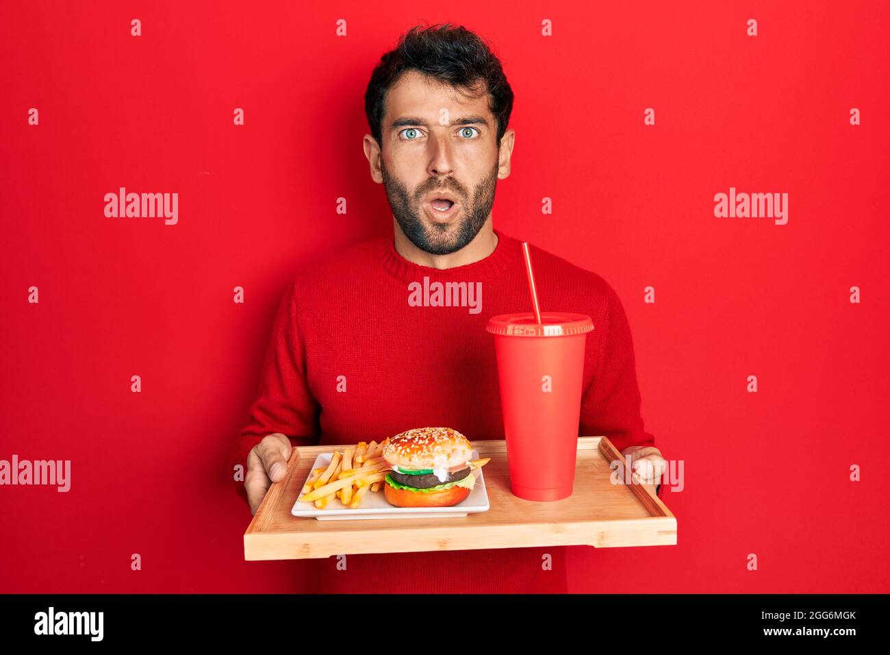 Handsome man with beard eating a tasty classic burger with fries and ...