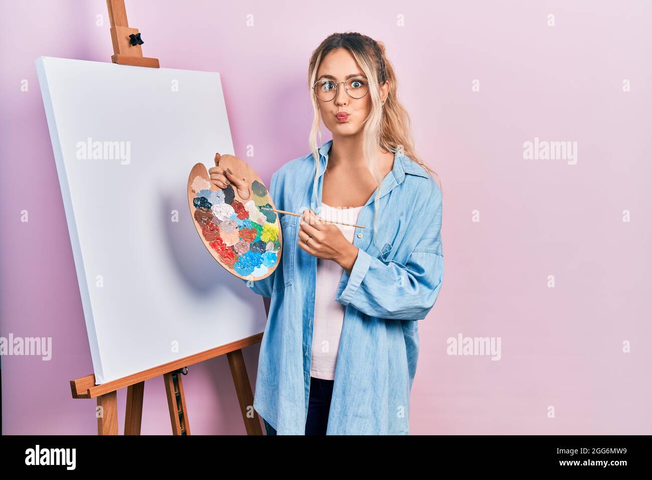 Beautiful young blonde woman standing drawing with palette by painter ...