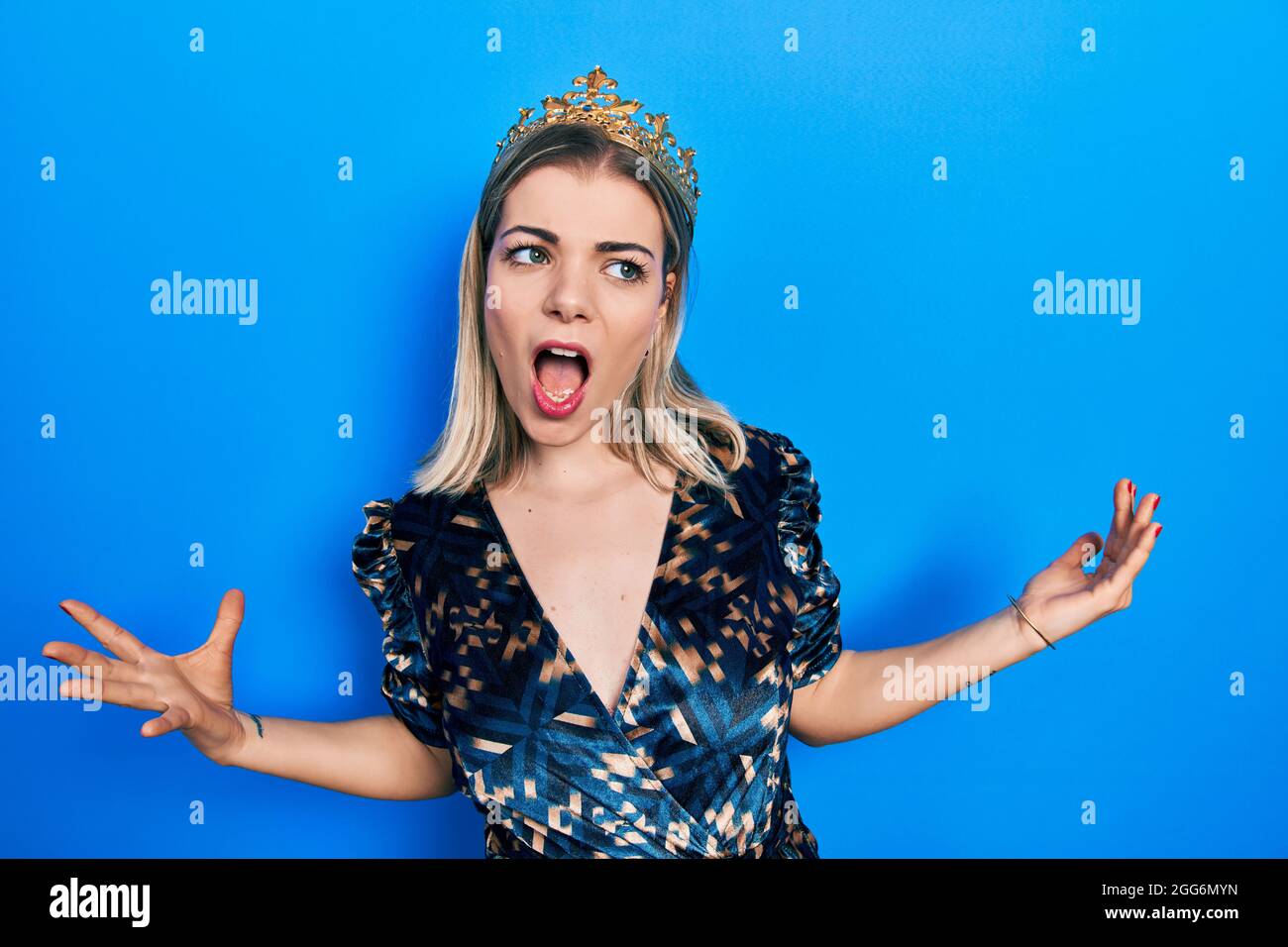 Beautiful caucasian woman wearing princess crown crazy and mad shouting ...