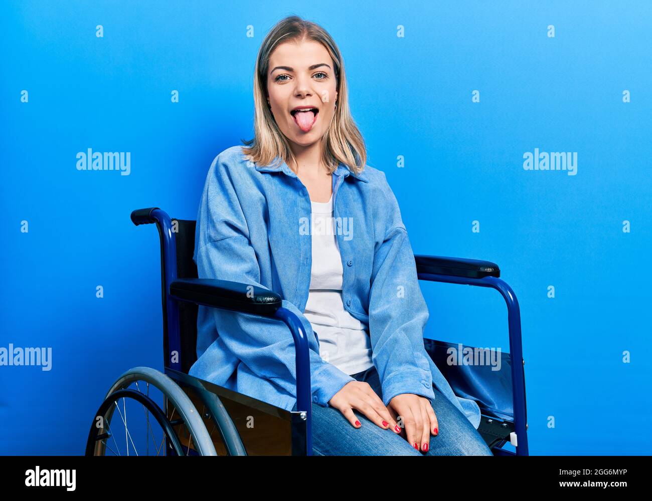 Beautiful caucasian woman sitting on wheelchair sticking tongue out ...