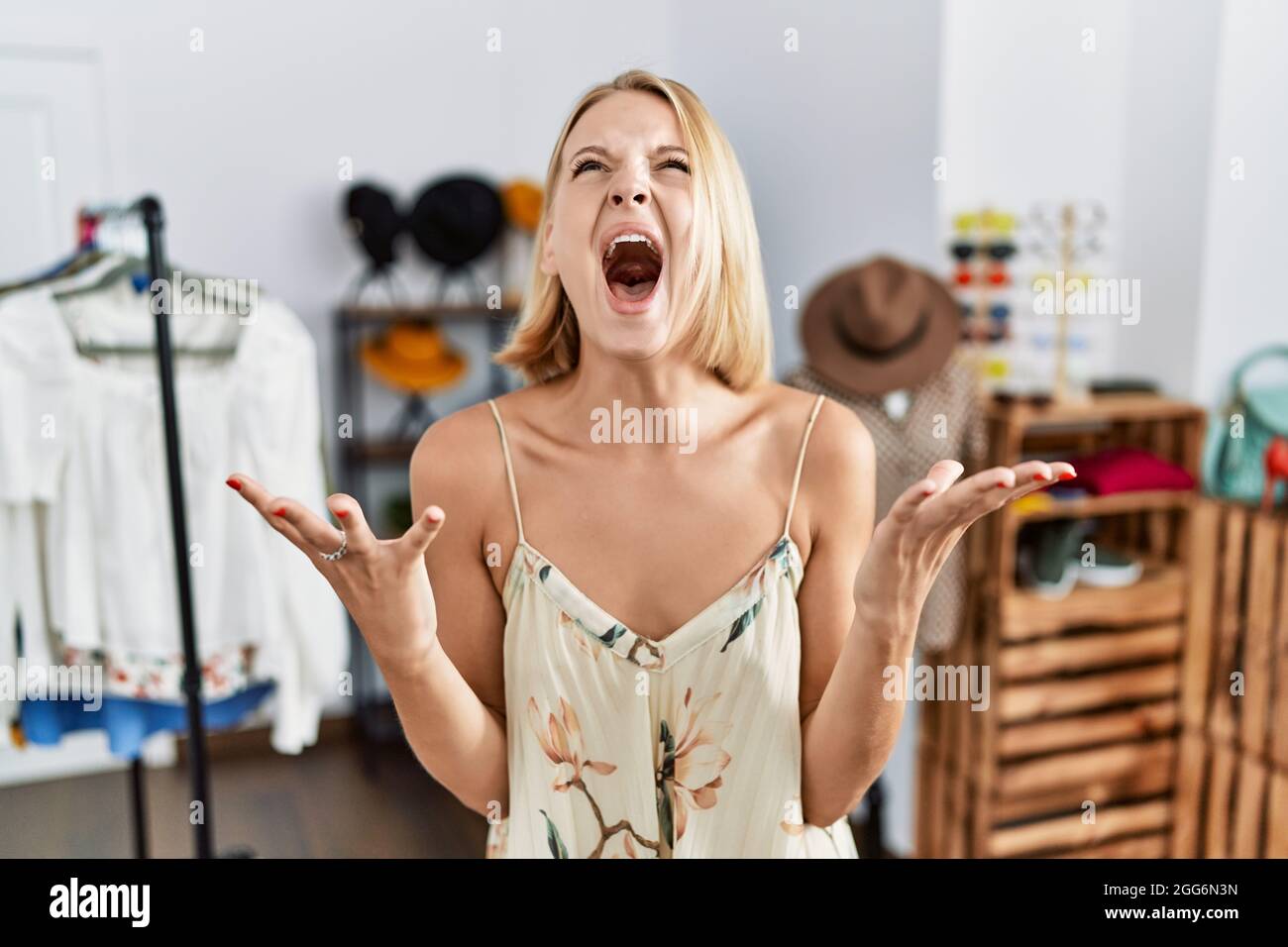 Young caucasian woman at retail shop crazy and mad shouting and yelling ...