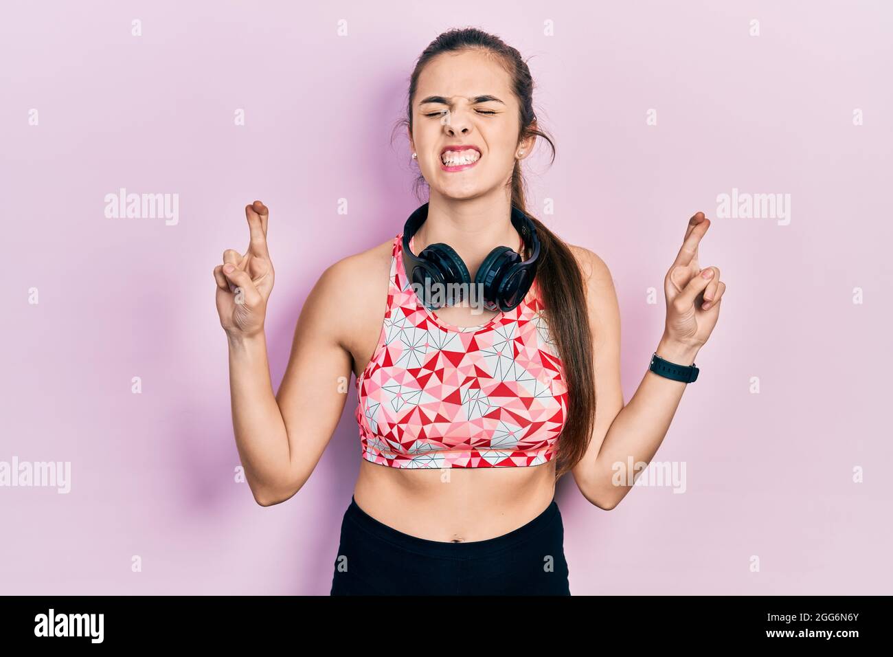Young brunette teenager wearing gym clothes and using headphones ...