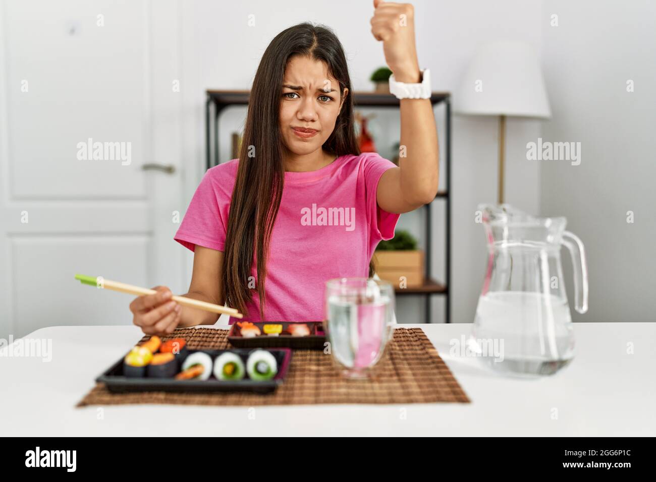 Young brunette woman eating sushi using chopsticks angry and mad ...