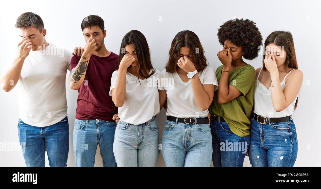Group of young friends standing together over isolated background tired ...