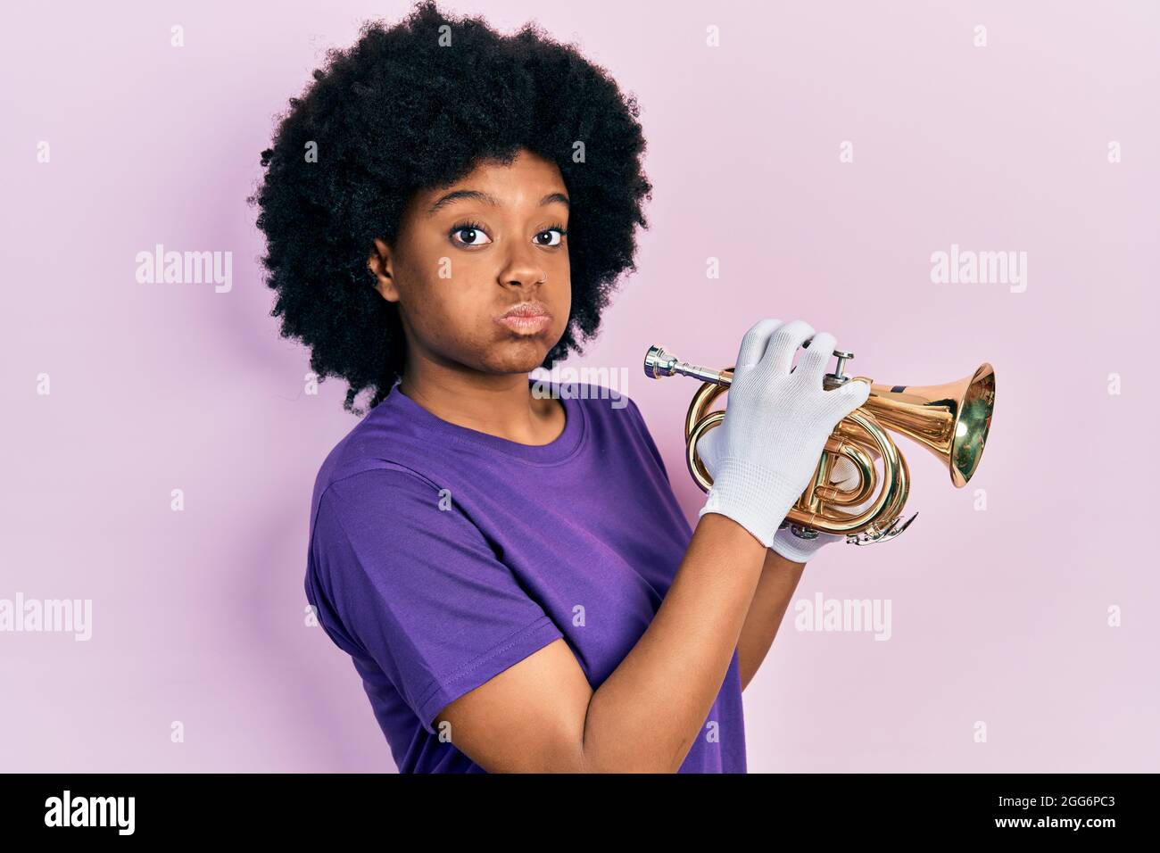 Young african american woman playing trumpet puffing cheeks with funny ...