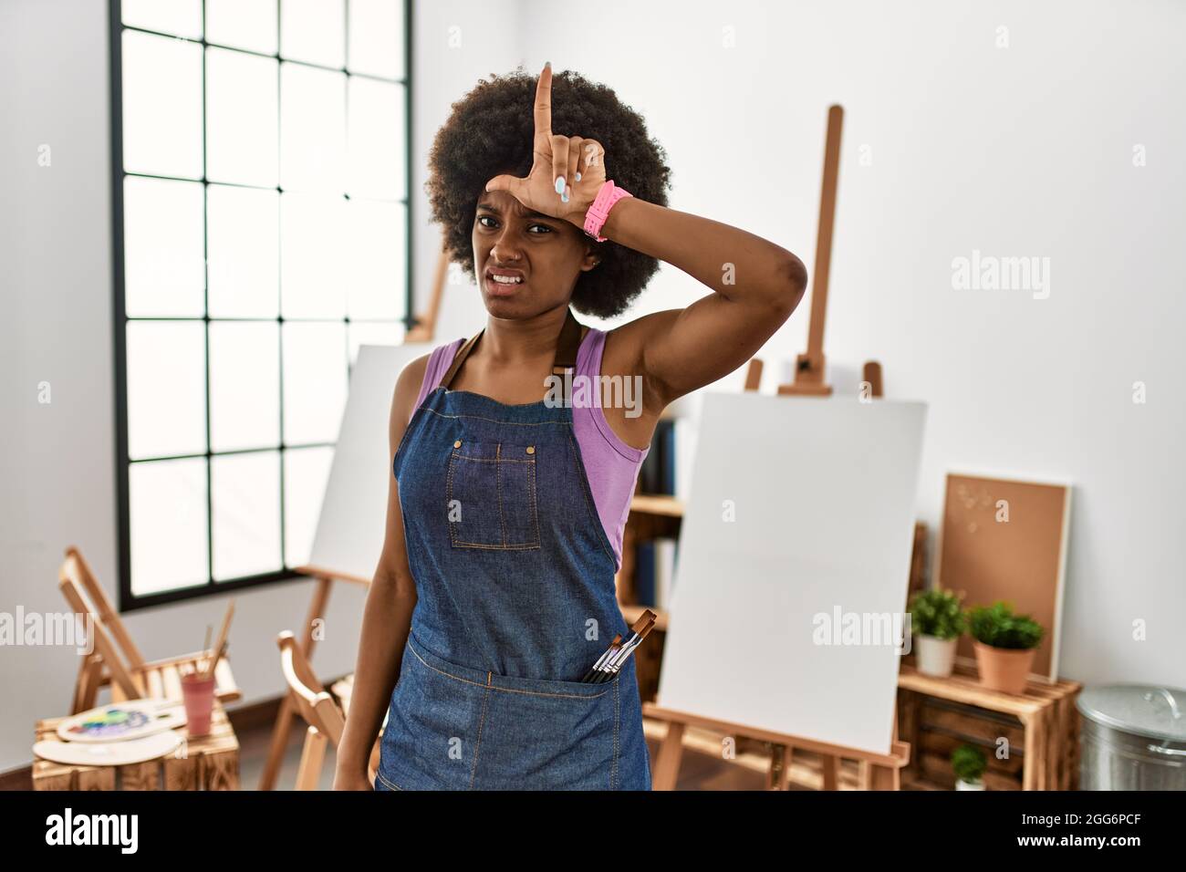 Young african american woman with afro hair at art studio making fun of ...