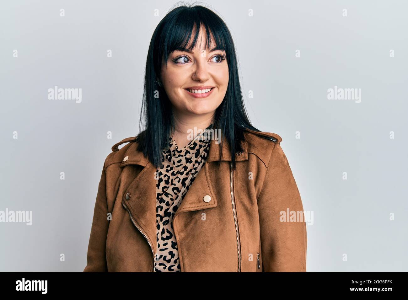 Young hispanic woman wearing casual leather jacket looking to side ...