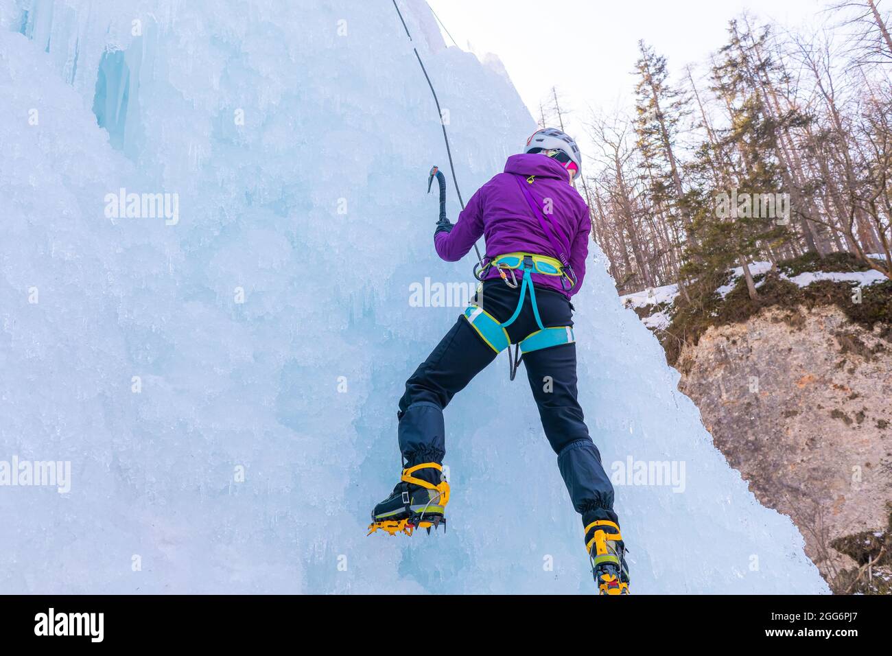 Female ice climber with ice climbing equipment, axes, helmet, harness ...
