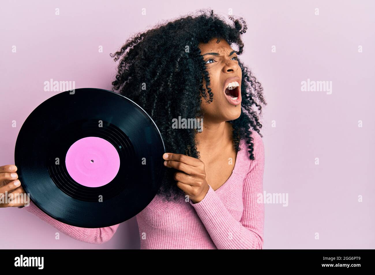 African american woman with afro hair holding vinyl disc angry and mad ...