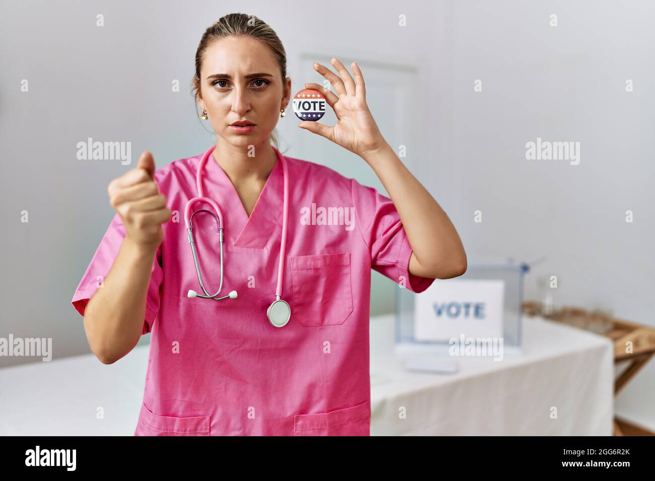 Young nurse woman at political campaign holding usa vote badge annoyed ...