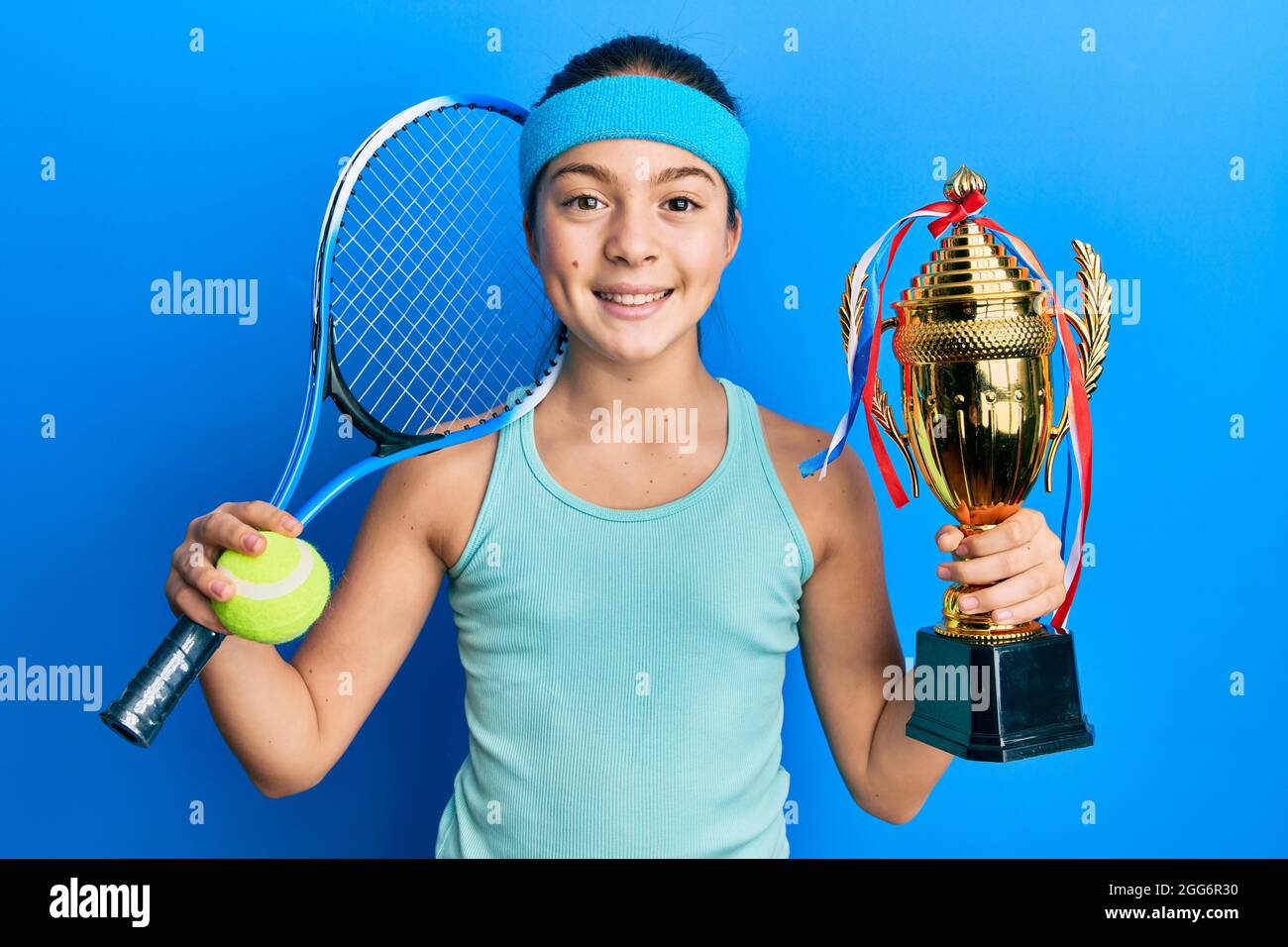 Beautiful brunette little girl playing tennis holding trophy smiling ...