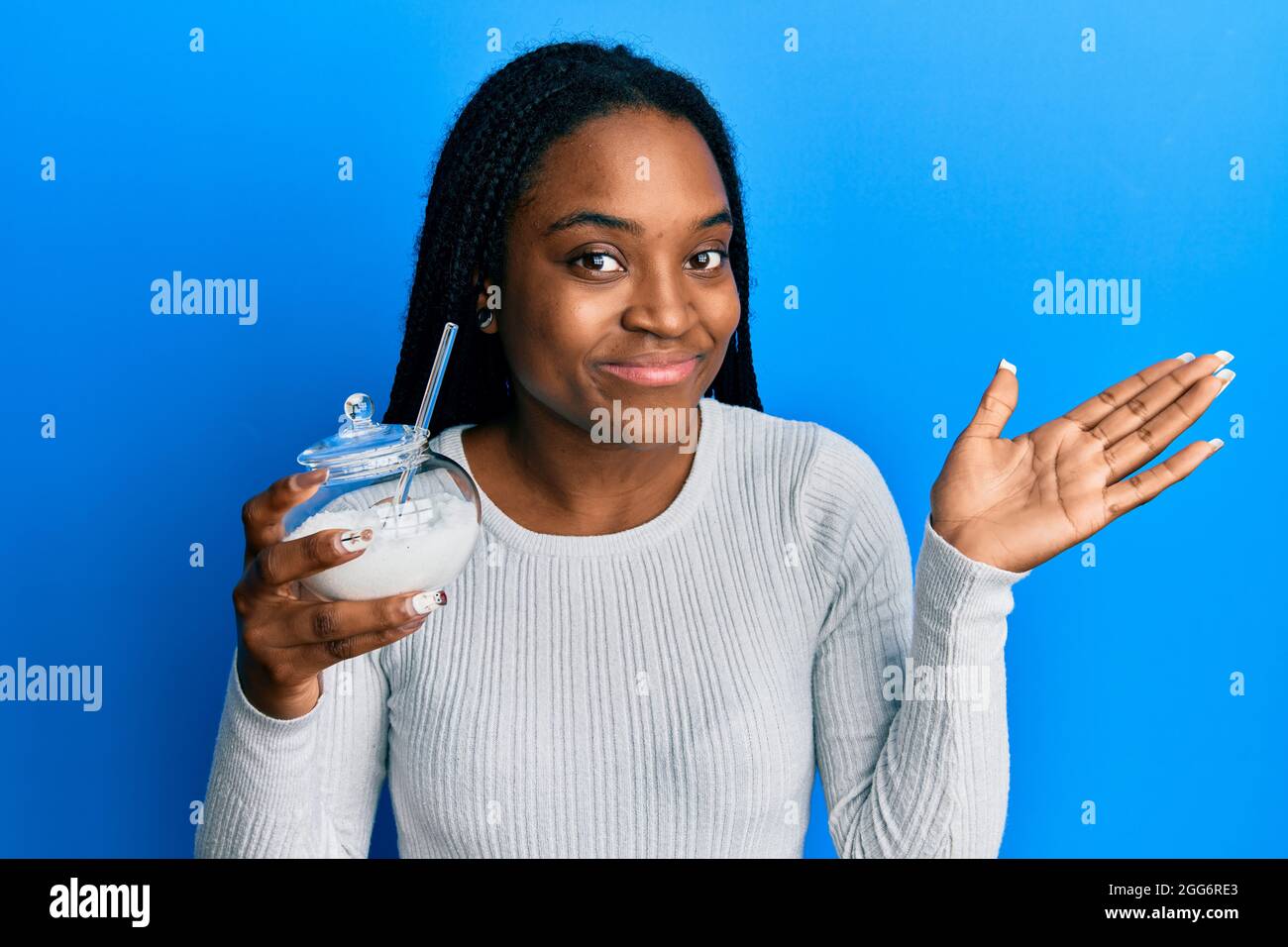 African american woman with braided hair holding bowl of sugar candy ...