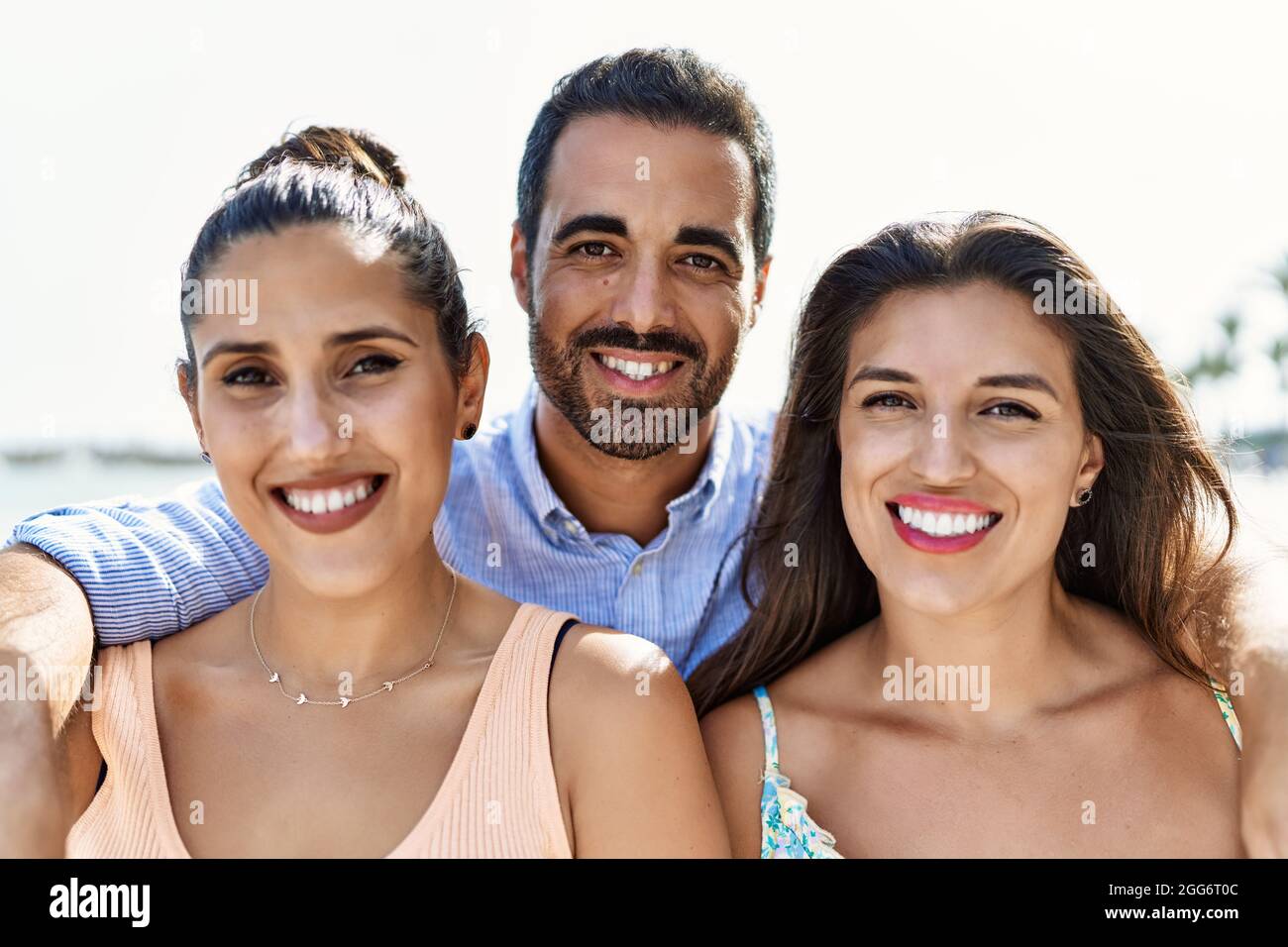 Three young hispanic friends smiling happy and hugging at the beach ...