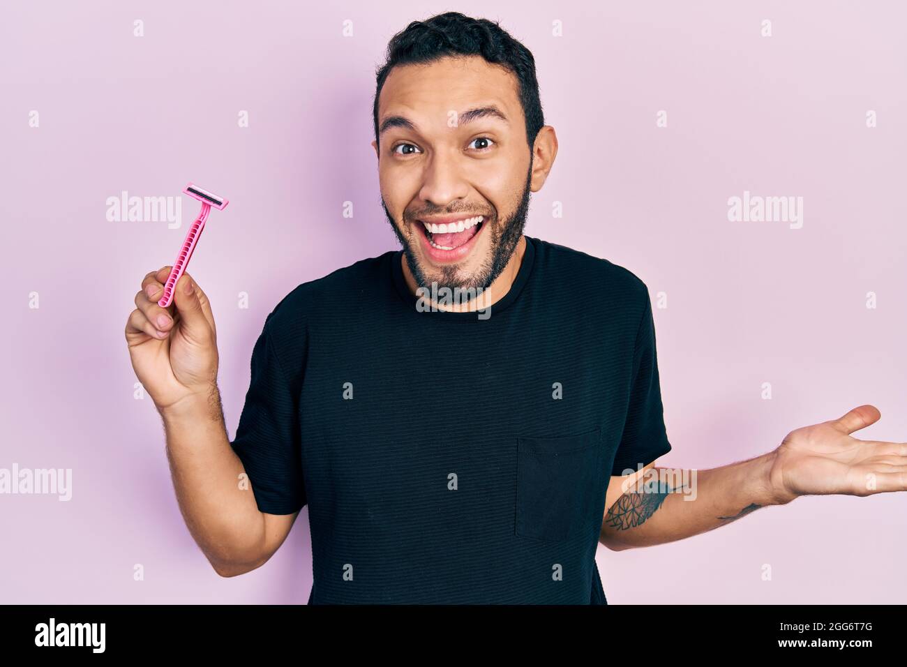 Hispanic man with beard holding razor celebrating achievement with ...