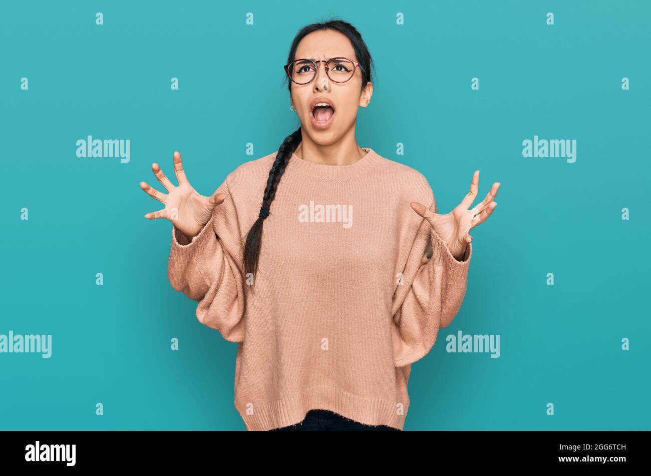 Young hispanic girl wearing casual clothes and glasses crazy and mad ...