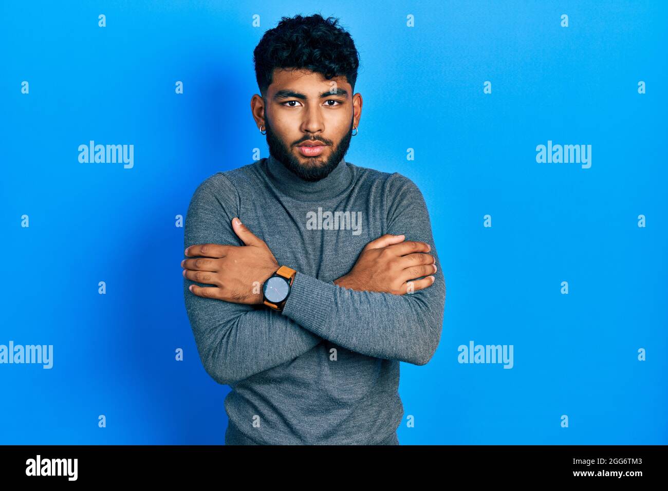 Arab man with beard wearing turtleneck sweater shaking and freezing for ...