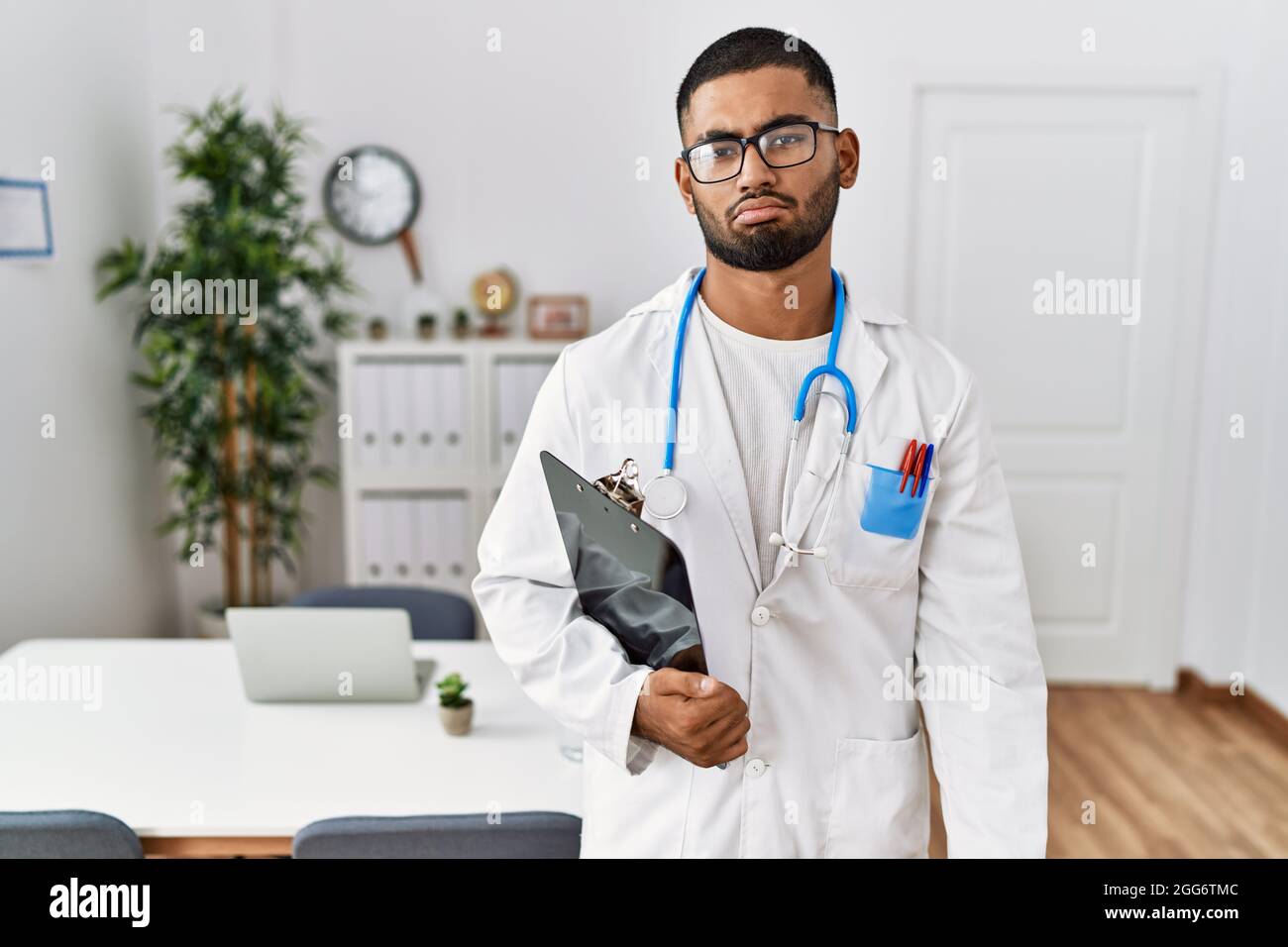 Young indian man wearing doctor uniform and stethoscope depressed and ...