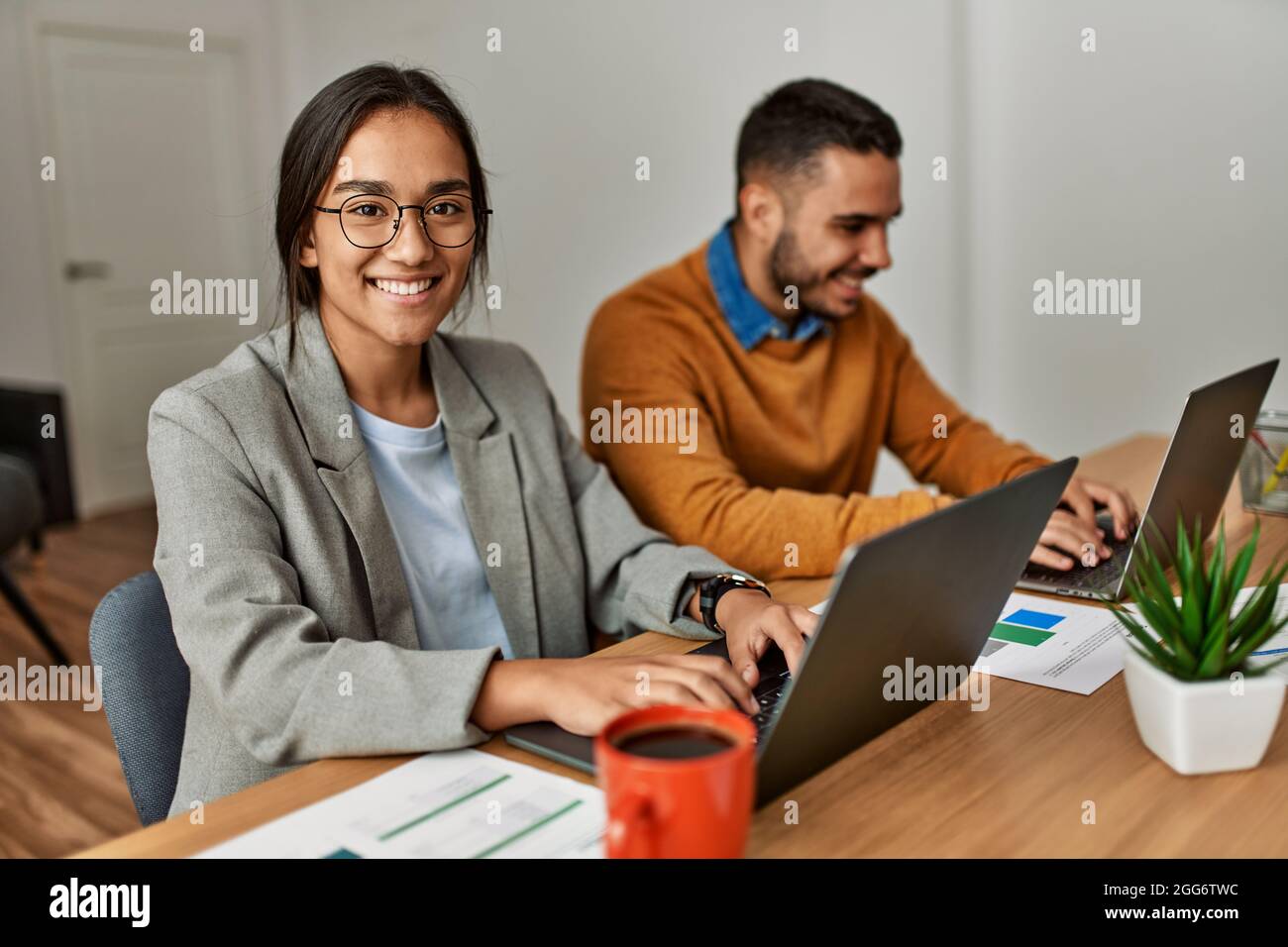 Two business workers smiling happy working sitting on desk at the ...
