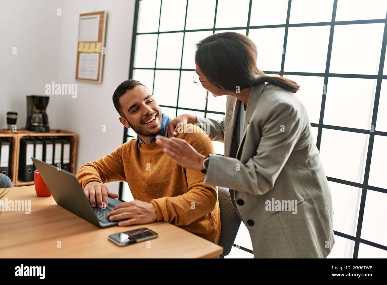 Two business workers smiling happy working sitting on desk at the ...