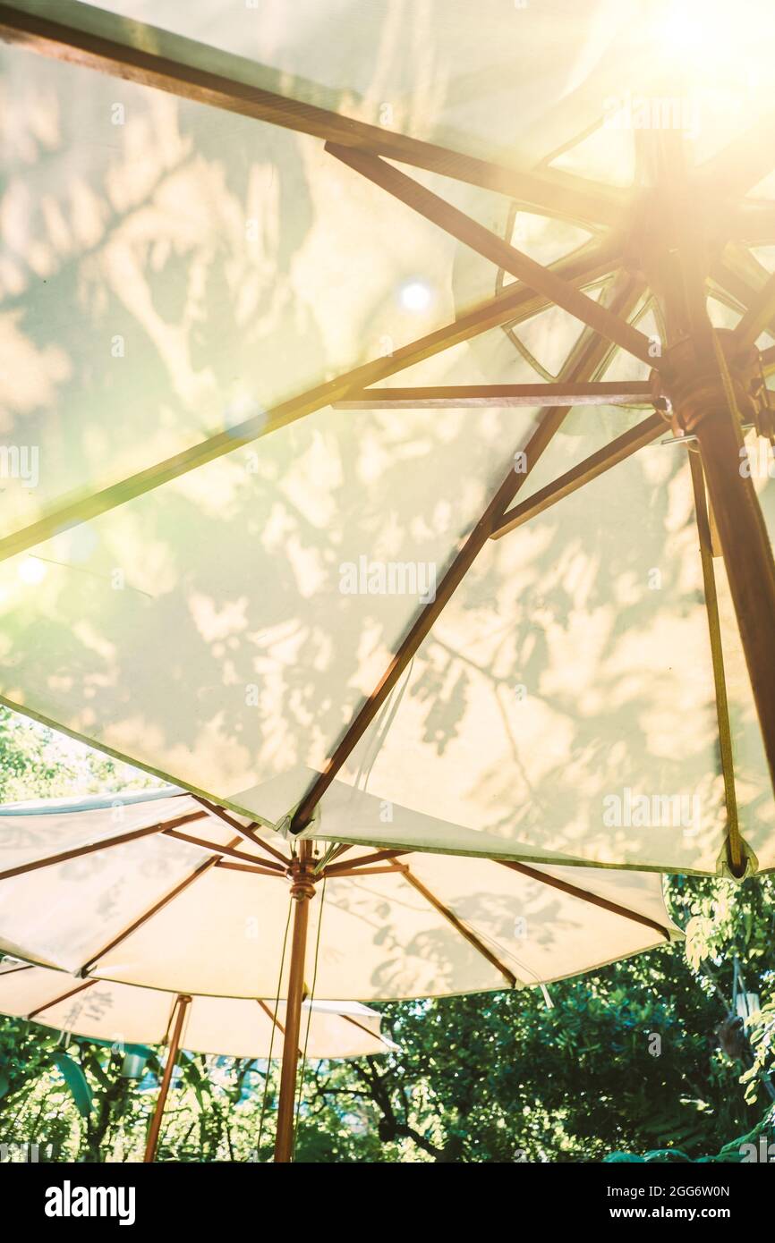 Sunlight through white parasol umbellar. Garden furniture function ...
