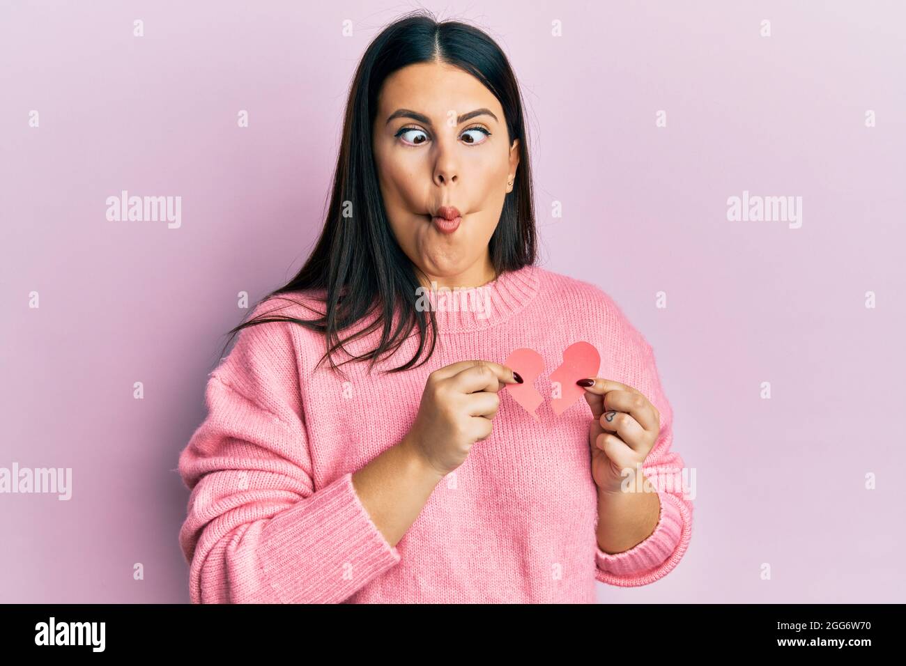 Beautiful brunette woman holding broken heart paper shape making fish ...