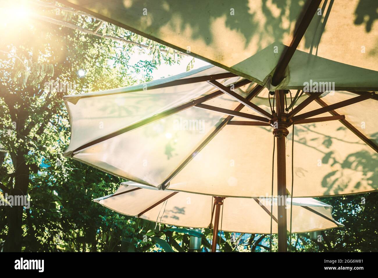 Sunlight through white parasol umbellar. Garden furniture function ...