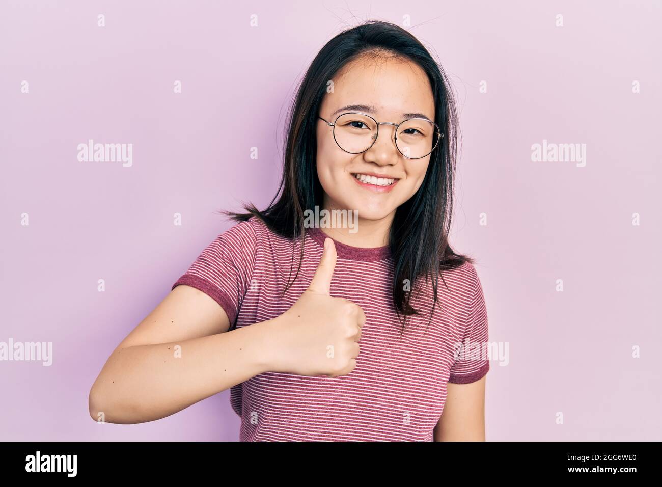 Young chinese girl wearing casual clothes and glasses doing happy ...