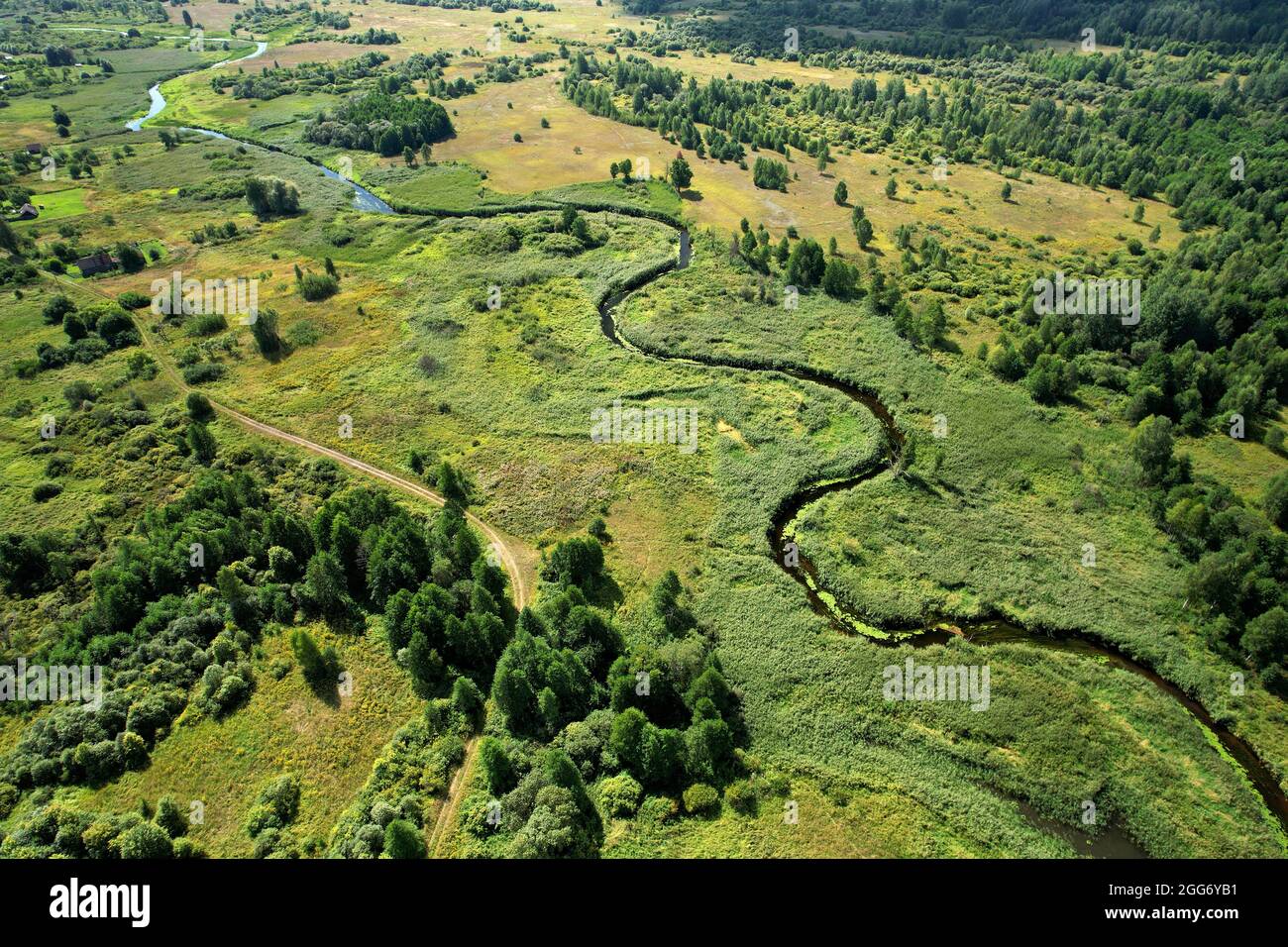 River in the wild. Aerial view of small river in middle of green field ...