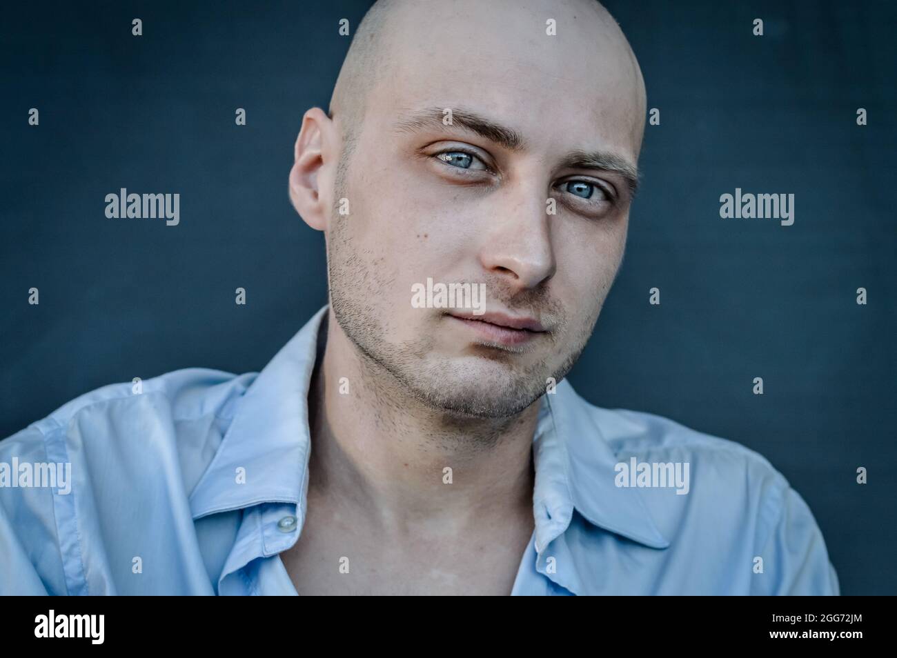 close up portrait of a young bald man with blue eyes and a blue shirt ...