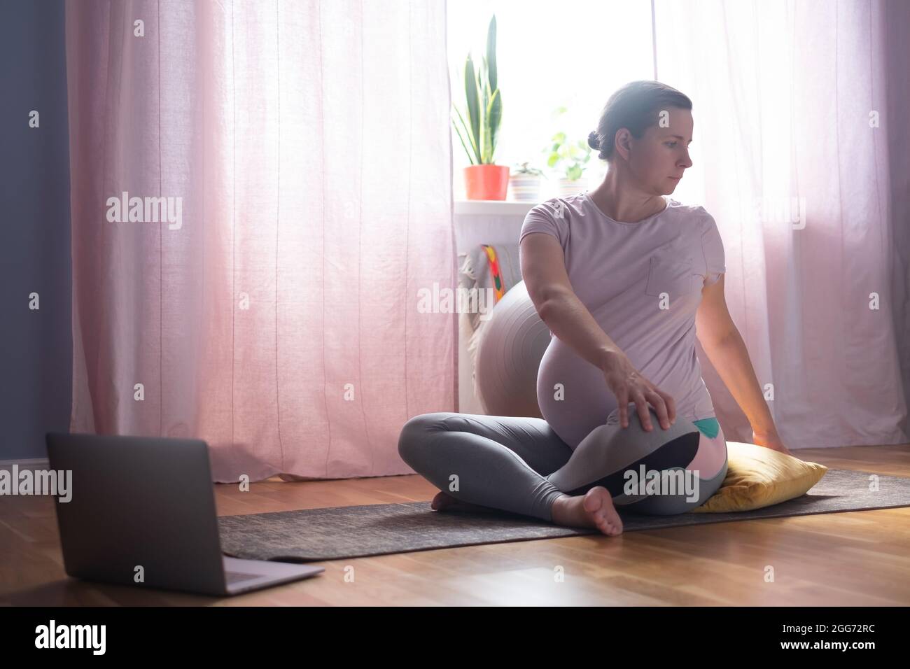 Pregnant woman sitting on floor stretching doing twisted asana Stock ...
