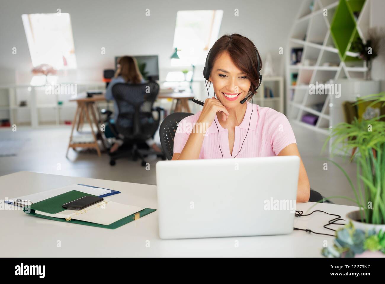 Customer service assistant wearing headset while sitting behind her ...