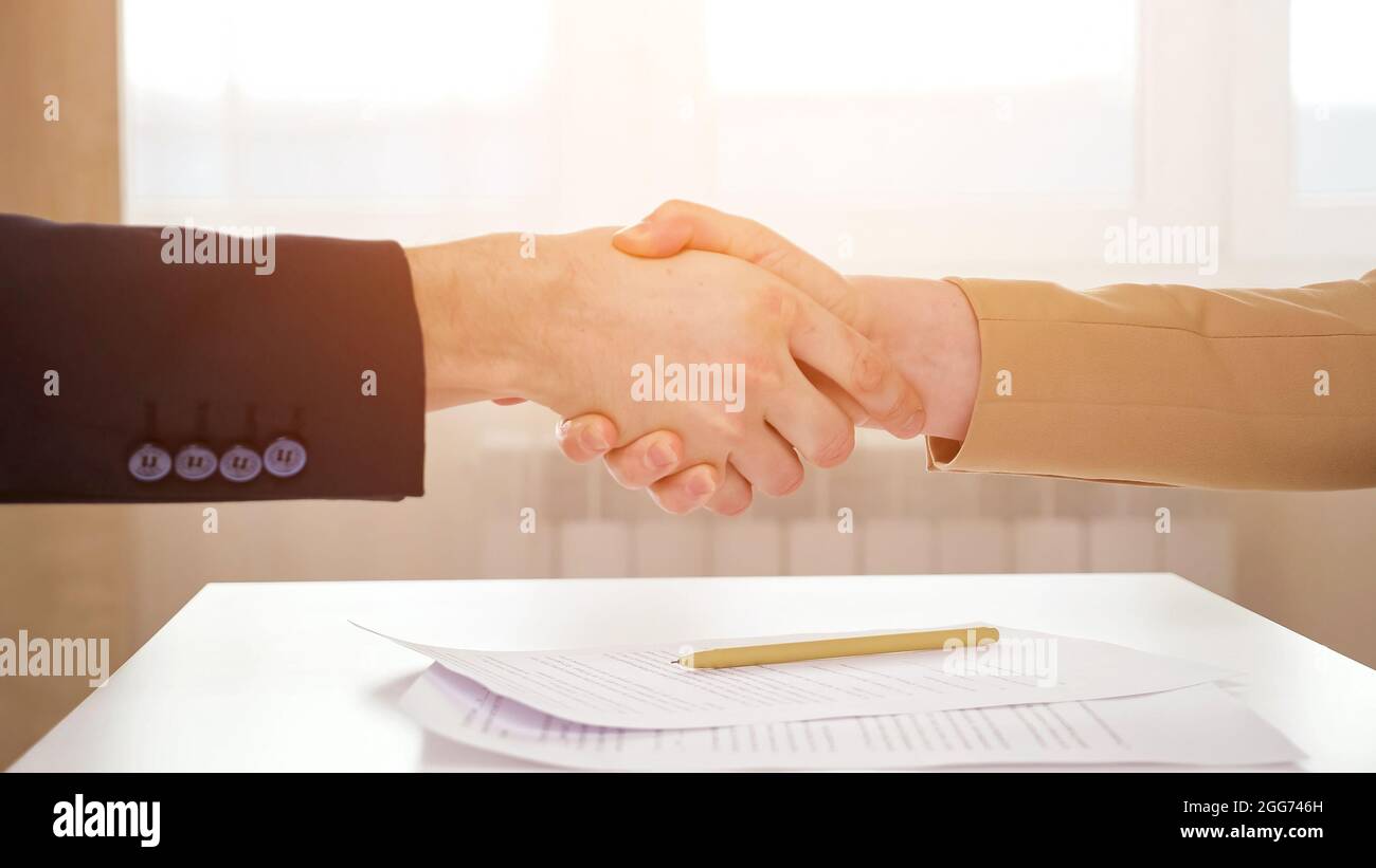 Manager and client shake hands above contract in office Stock Photo - Alamy