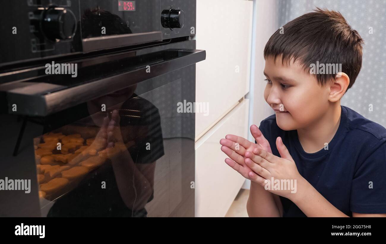 boy sits and looks into the oven while waiting for a cookie Stock Photo ...