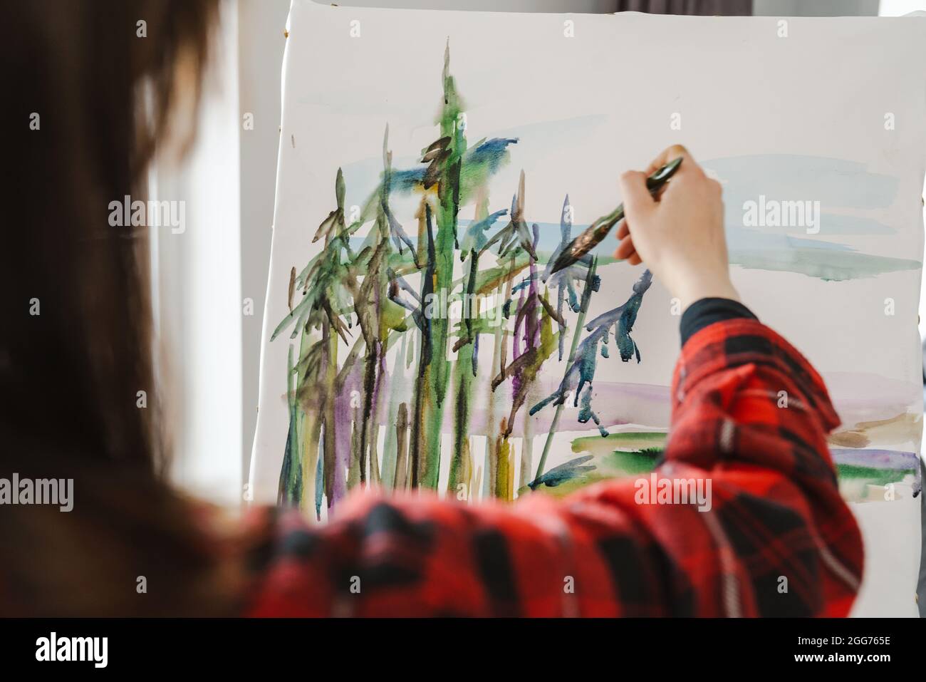 Young white woman painter holding paintbrush standing at the canvas ...