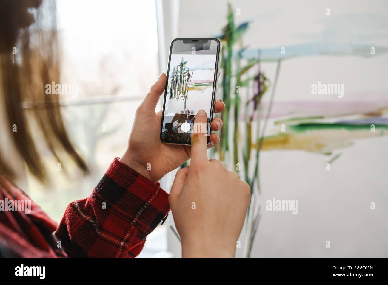 Young white woman painter holding paintbrush standing at the canvas ...