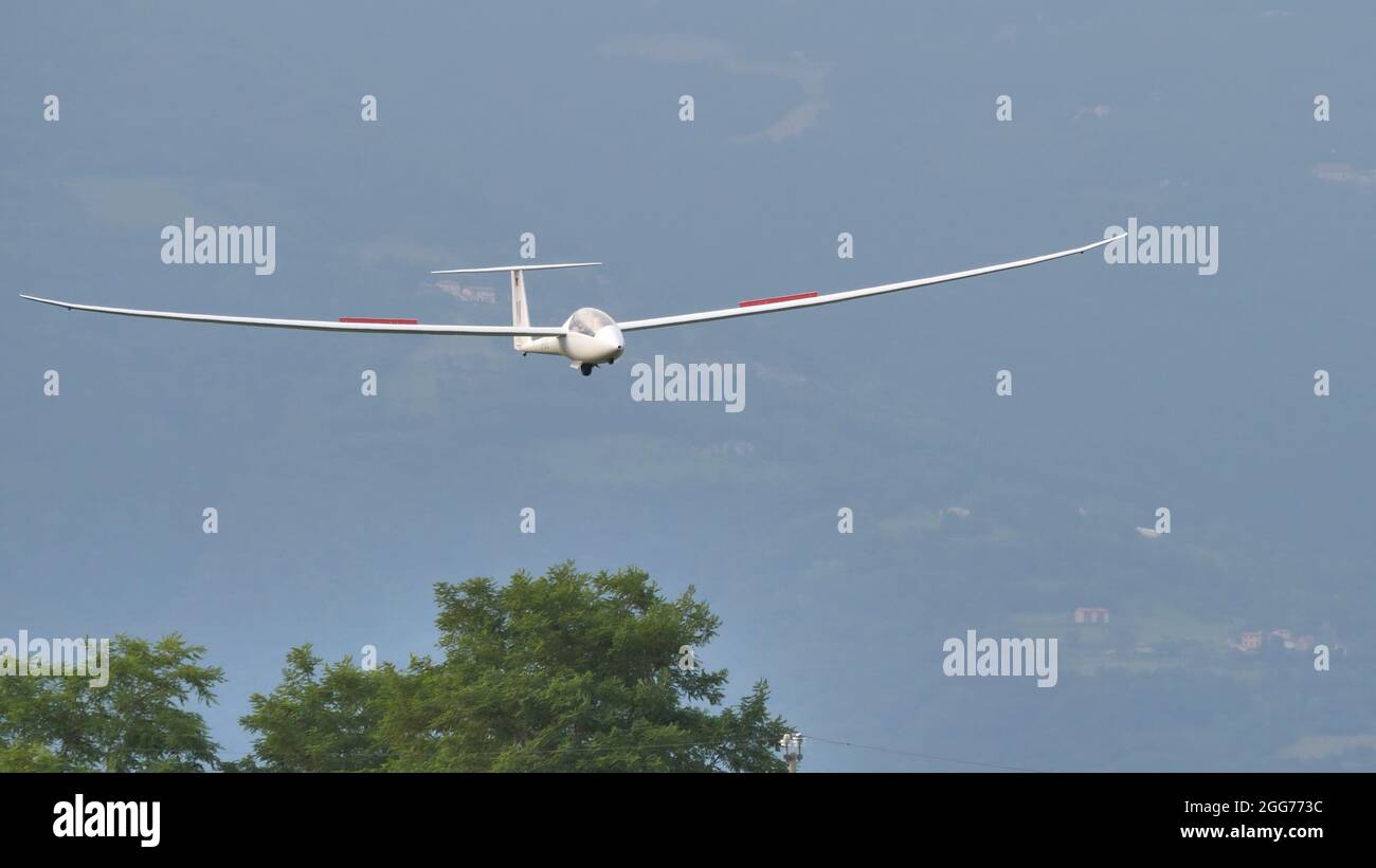 Thiene, Italy JULY, 8, 2021 Glider landing with the green alps in the ...