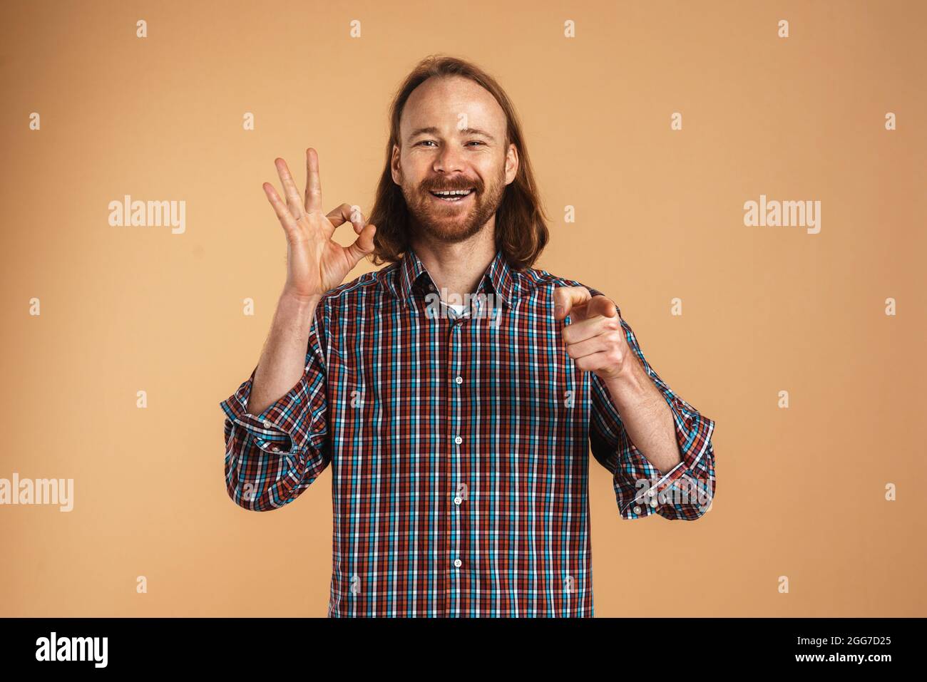 Ginger smiling man showing ok sign and pointing finger at camera ...
