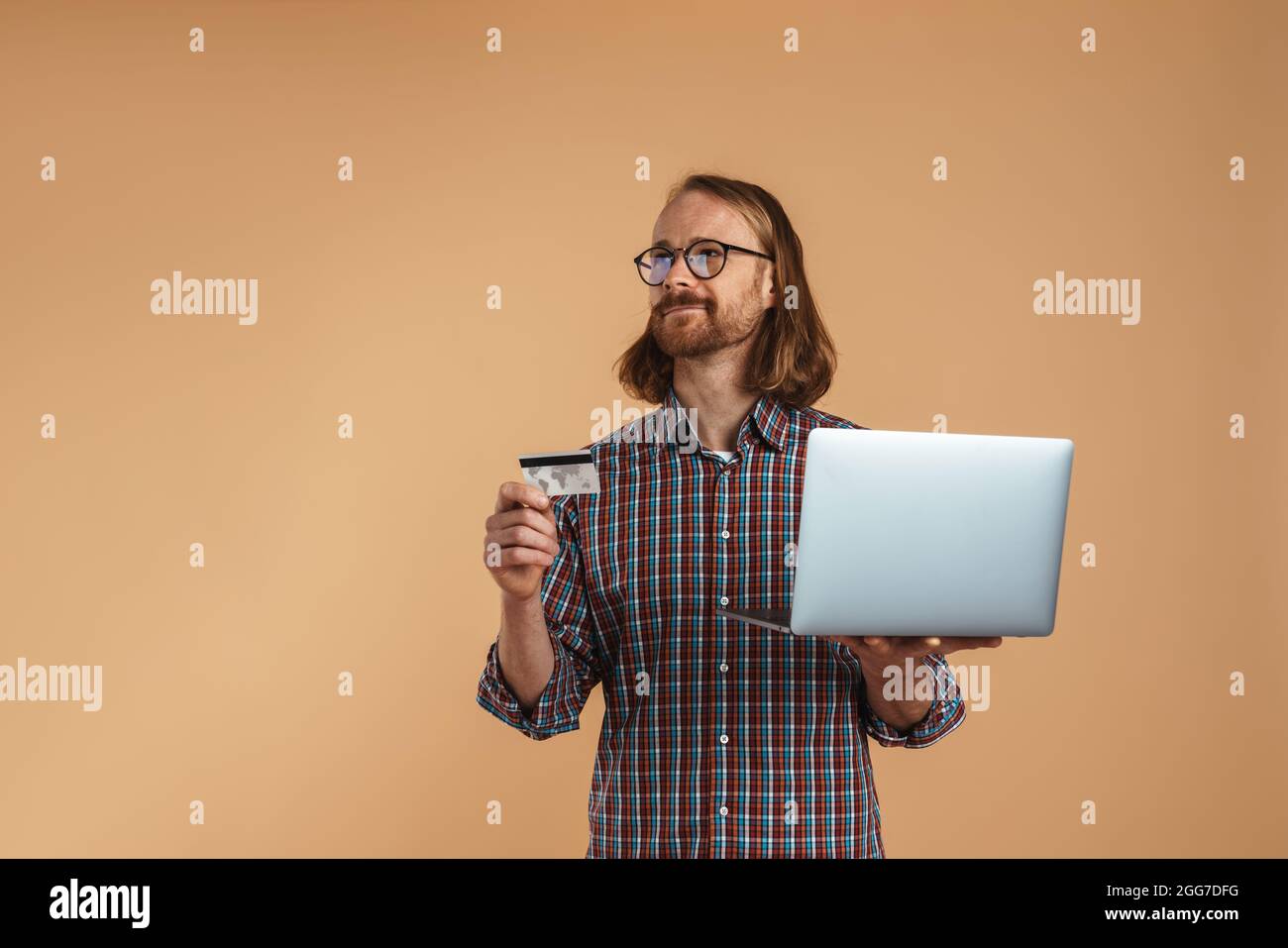 White ginger man wearing eyeglasses posing with laptop and credit card ...