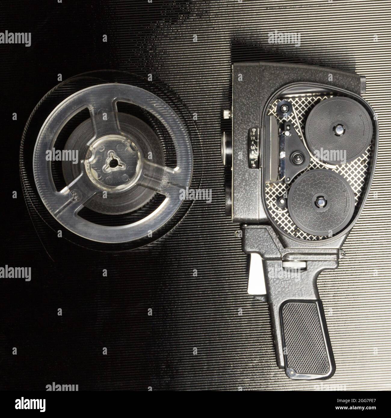 Old amateur movie camera and reel of film stock on black background ...