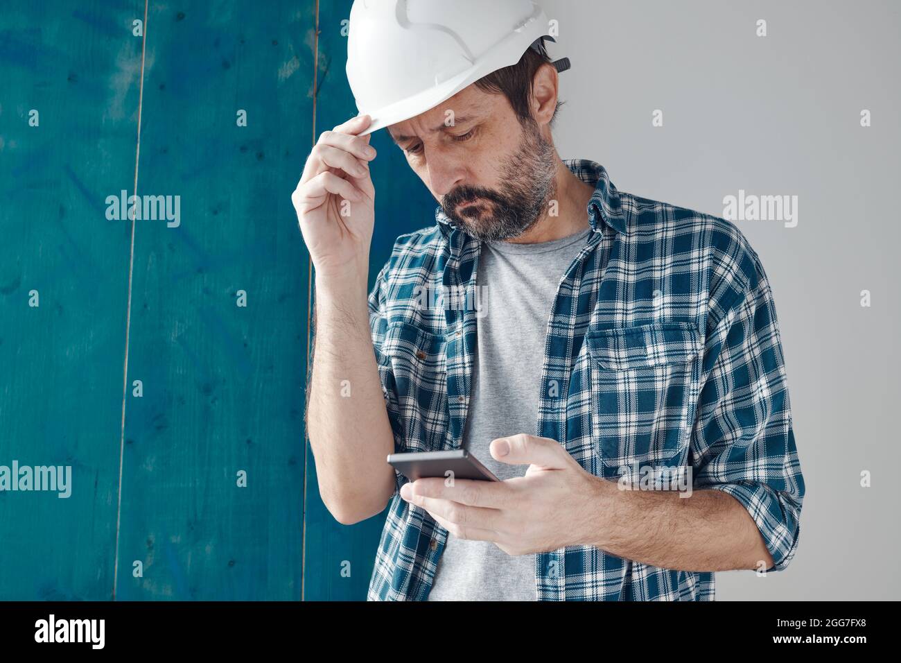 Construction engineer using smart phone on a morning break, relaxing ...