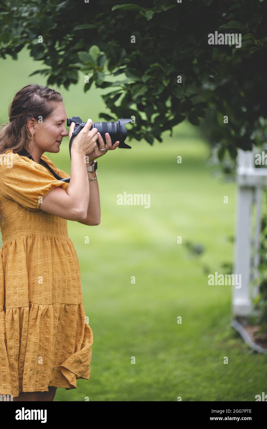 A vertical shot of a female Caucasian photographer taking photos of ...