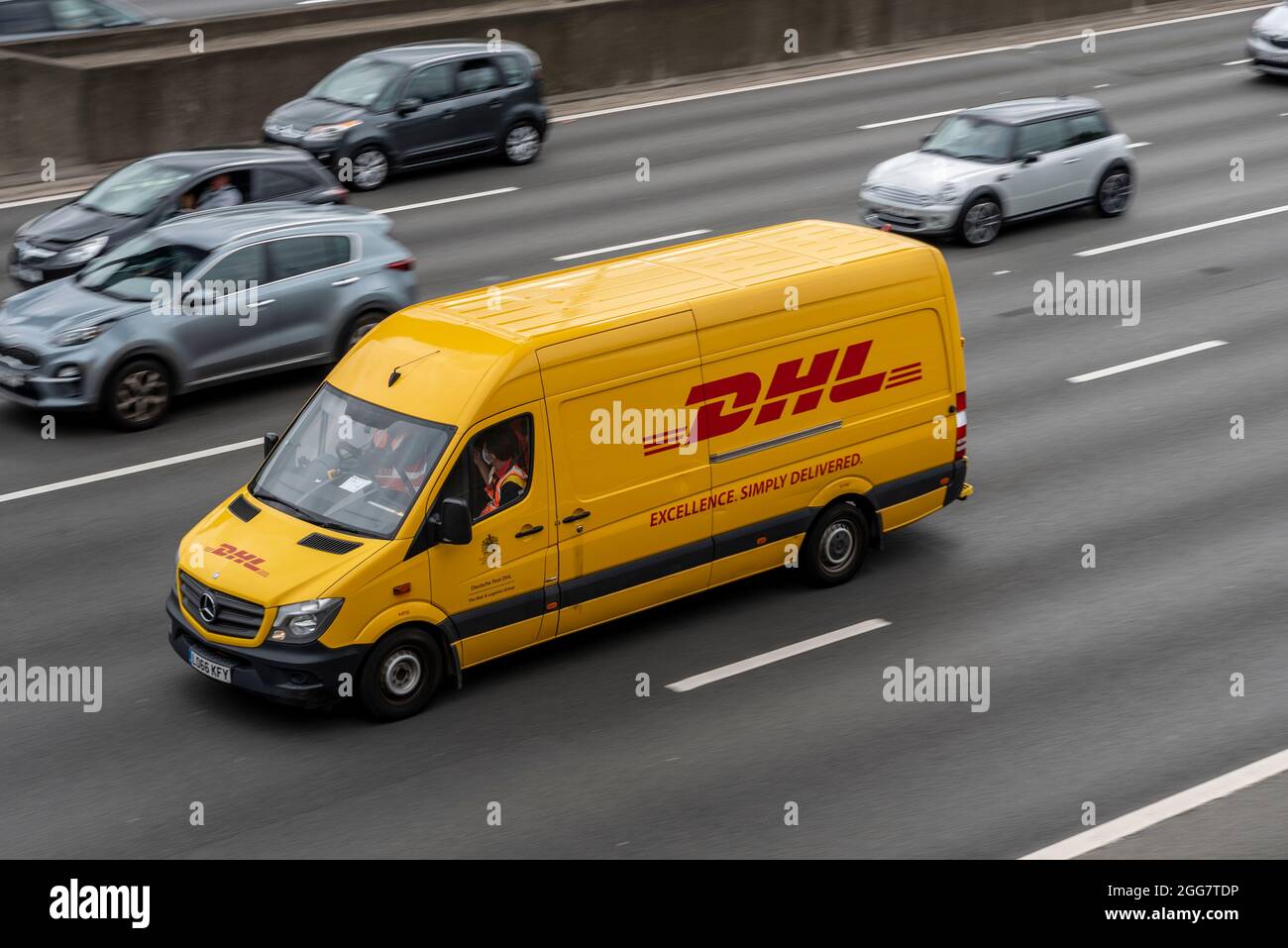 DHL van driving at speed on the M25 with cars. Yellow Stock Photo - Alamy
