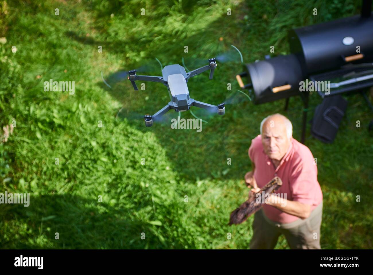 Old upset senior man upset by a flying drone over his garden. The ...