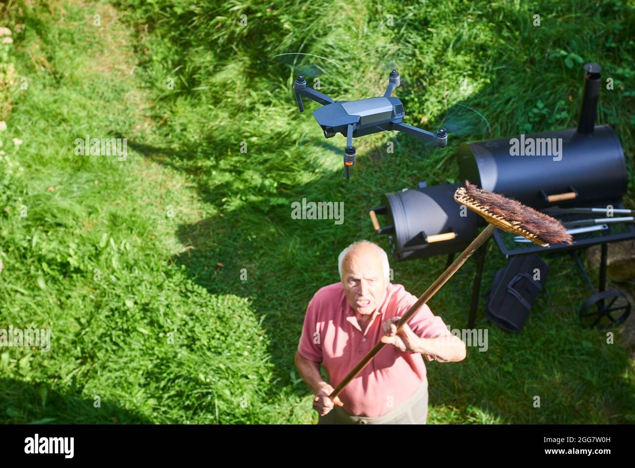 Old upset senior man upset by a flying drone over his garden. The ...