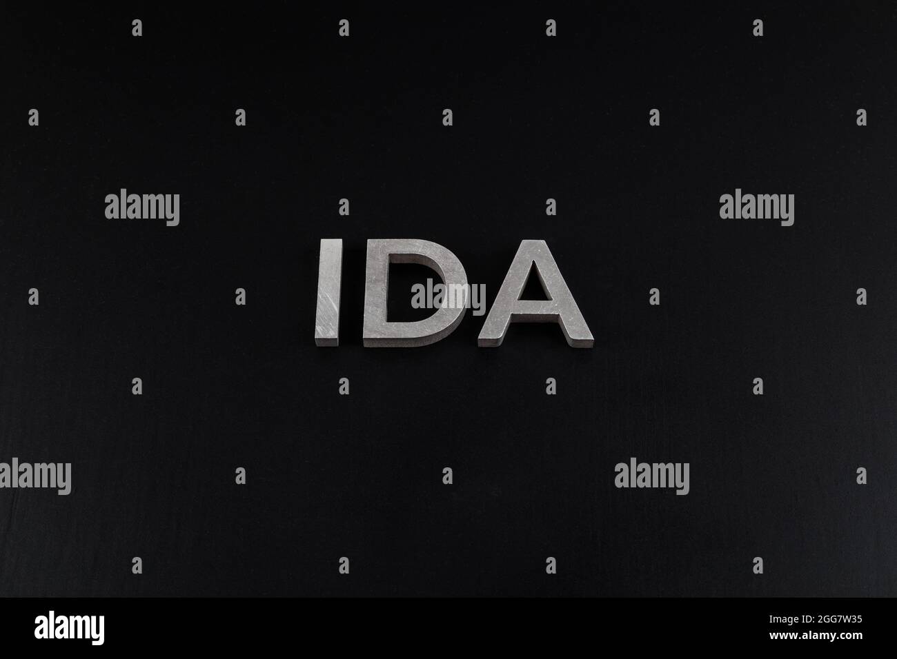 the word ida laid with silver metal letters over dry black matte ...