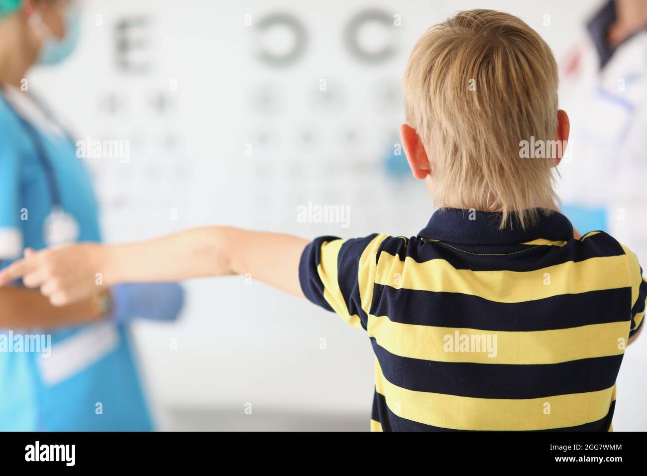 Little boy stands in the ophthalmologists office in front of the stands ...